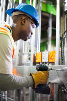 African American worker drilling metal on site - Stock Image - Everypixel