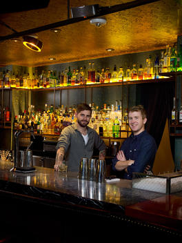 Two men stand smiling behind a bar at a pub - Stock Image - Everypixel