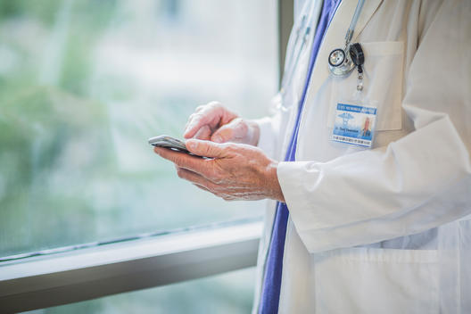 Caucasian doctor using cell phone - Stock Image - Everypixel