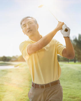 Chinese man playing golf on course - Stock Image - Everypixel